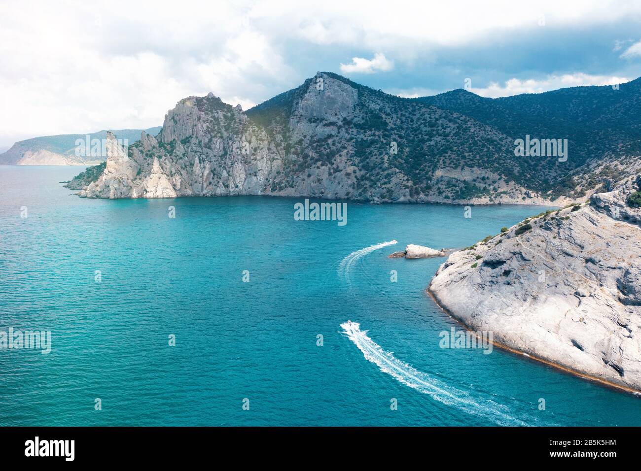 view of the rocks by the sea with a boat Stock Photo - Alamy