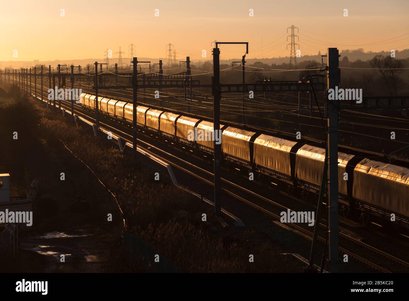 Rail freight wagons for carrying coal glinting in the setting sun on ...