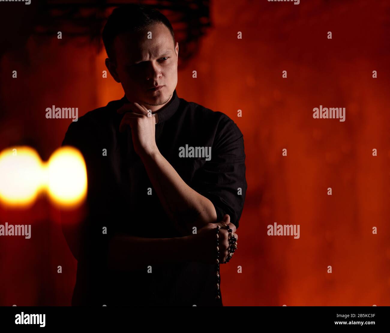 Young adult caucasian catholic priest on dark red background Handsome ...