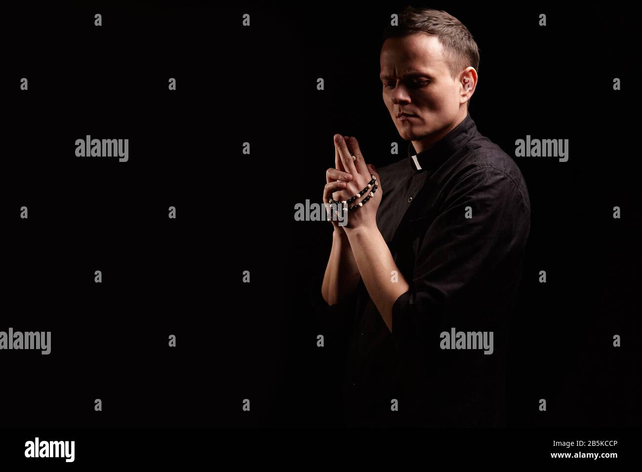 Young adult caucasian catholic priest on dark red background Handsome ...