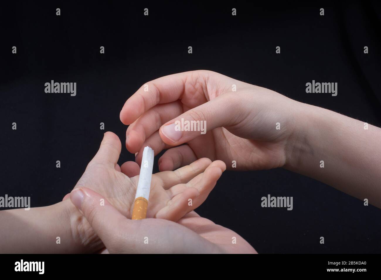 Hand is giving out cigarette on a black background Stock Photo - Alamy