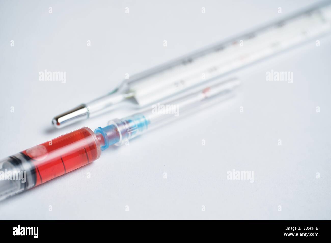 Syringe with medicine red for lowering temperature next to a ...