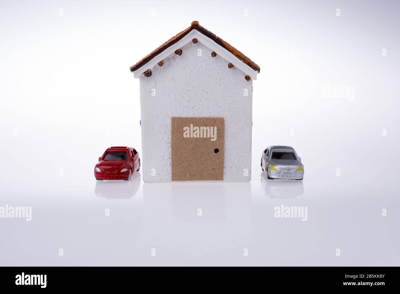 Little model house and two cars on a white background Stock Photo - Alamy