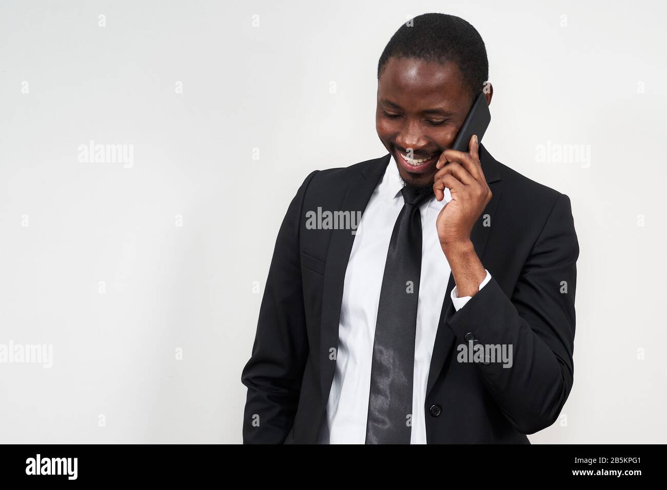 Portrait of african man smiling while talking on the phone with grey ...