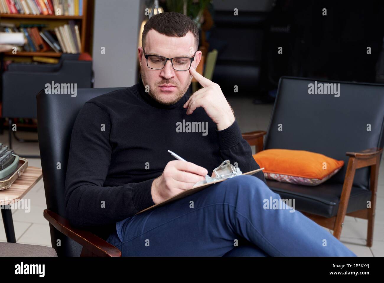Therapist writing down notes during therapy sitting in a chair Stock ...
