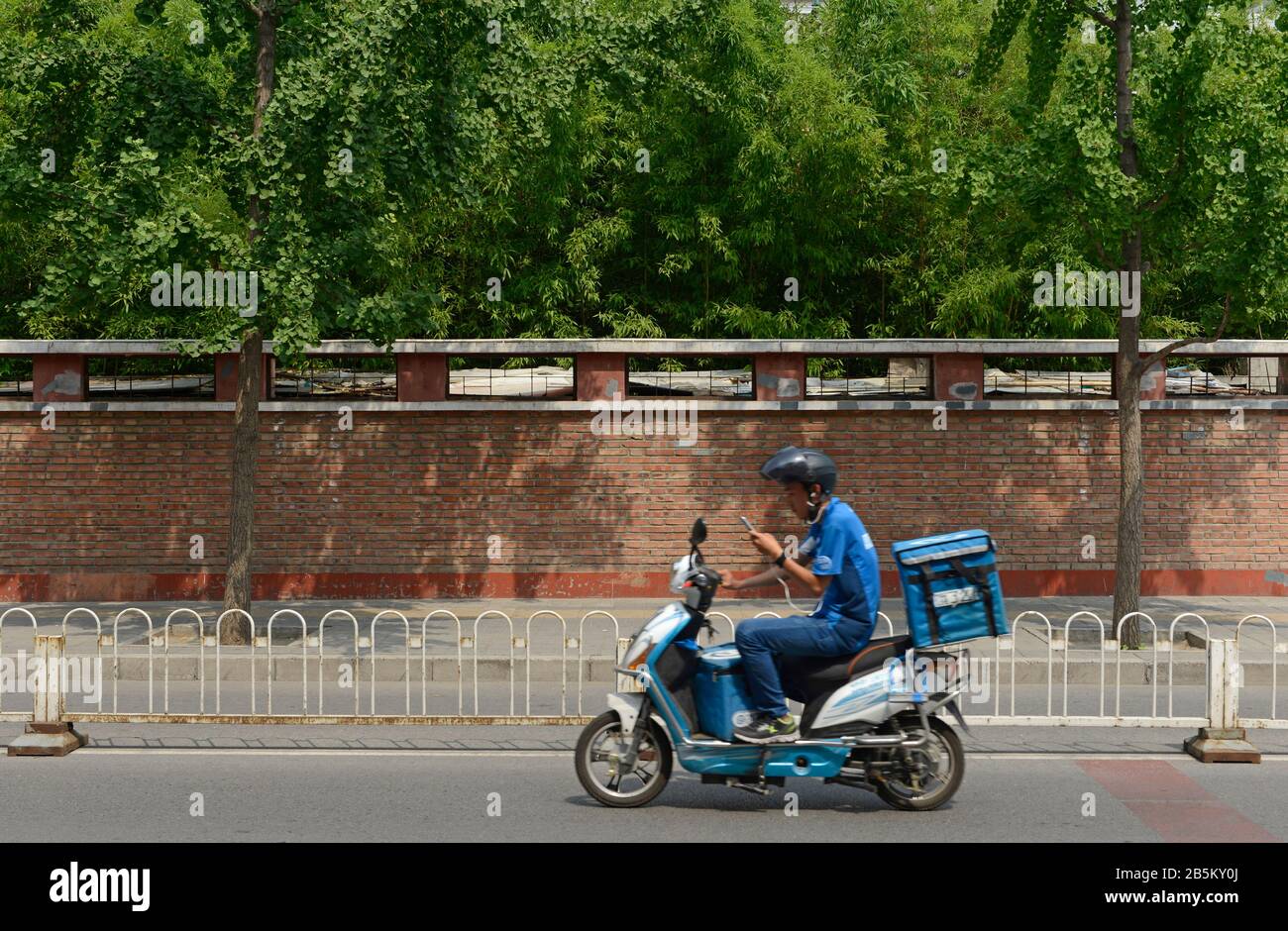 A delivery scooter driver checks his phone en route, Tuanjiehu, eastern ...
