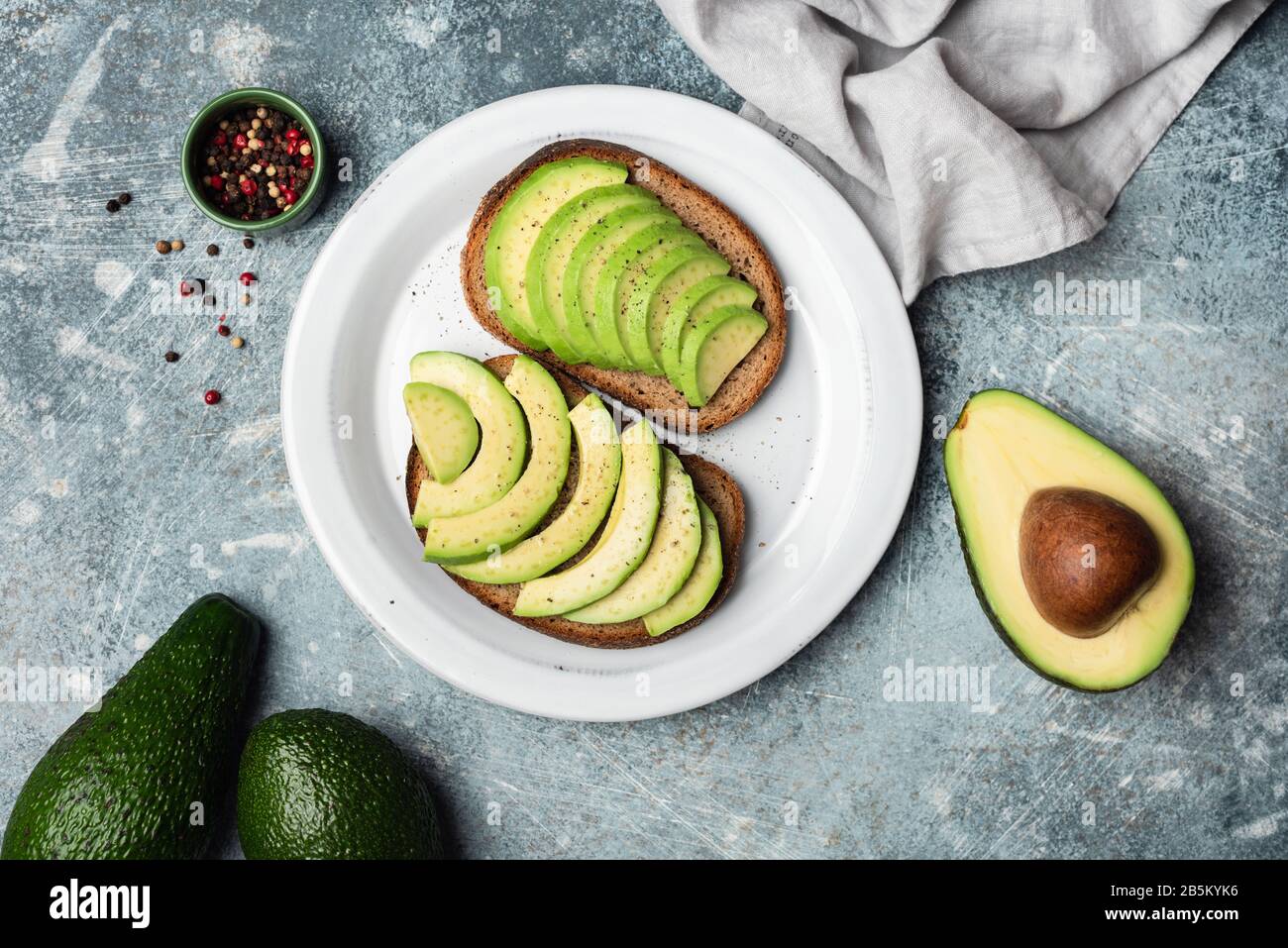 Rye bread toast with sliced avocado on plate, table top view. Healthy ...