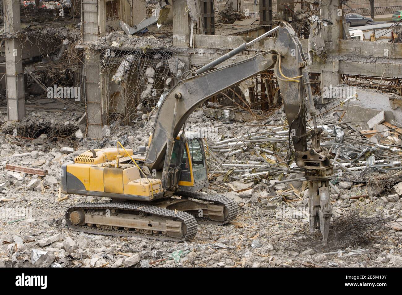 Hydraulic scissor excavator sorts scrap metal at construction site ...