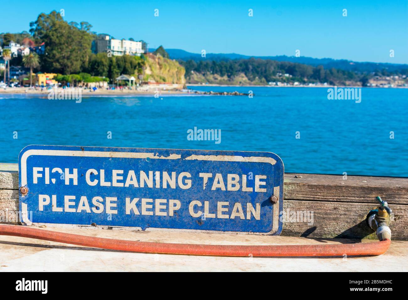 Empty public fish cleaning table sign on the pier. Beautiful coastal ...