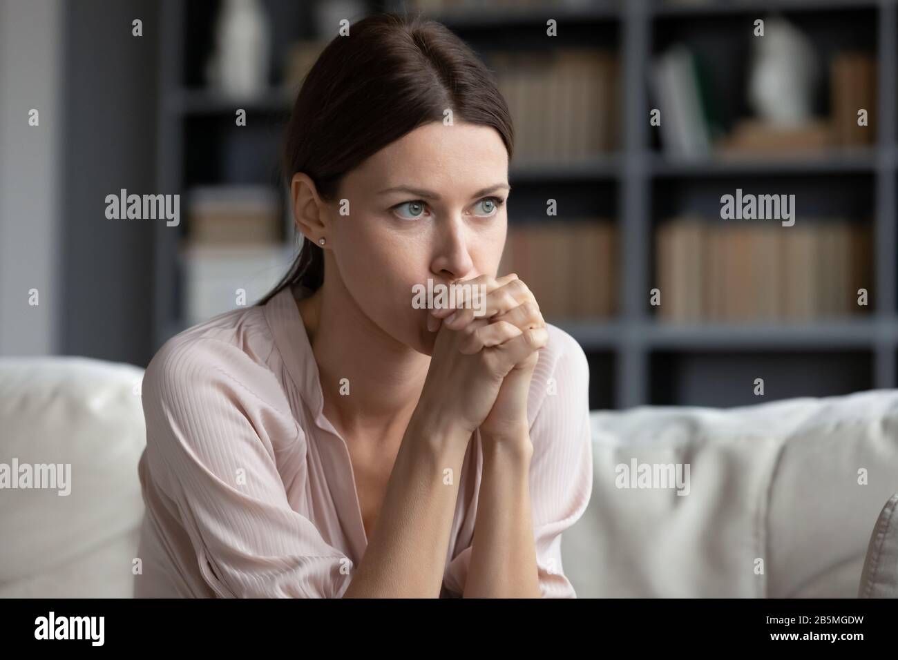Stressed young woman sitting on couch, worrying about problems Stock ...