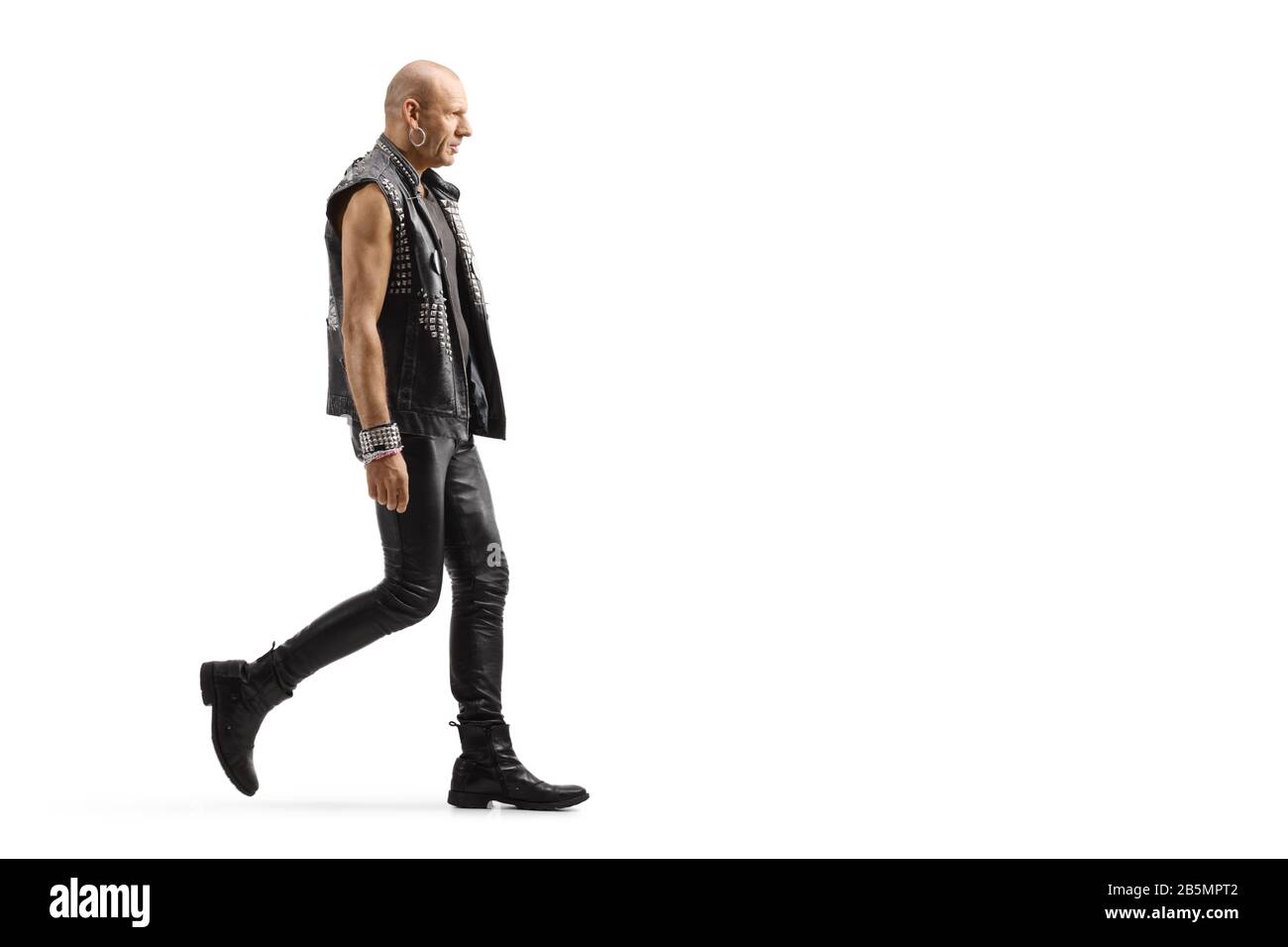 Full length profile shot of a bald punk man in leather clothes walking ...