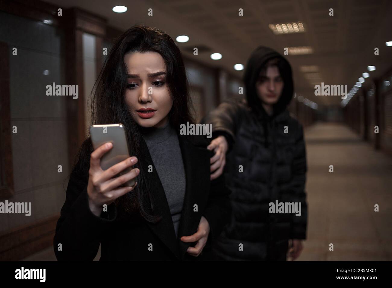 a young beautiful woman walks through the underpass at night, followed ...