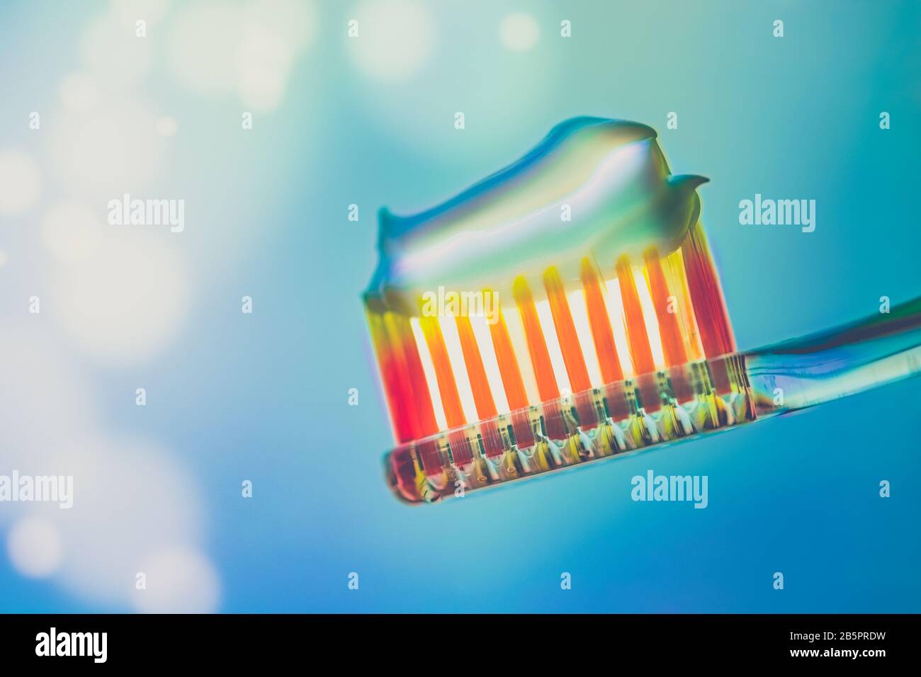 Orange plastic toothbrush with a toothpaste on a blue background. Side ...