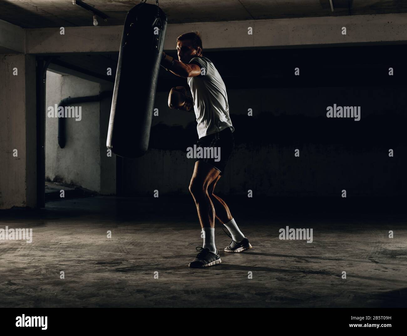 Muscular handsome fighter giving a forceful forward kick during a ...