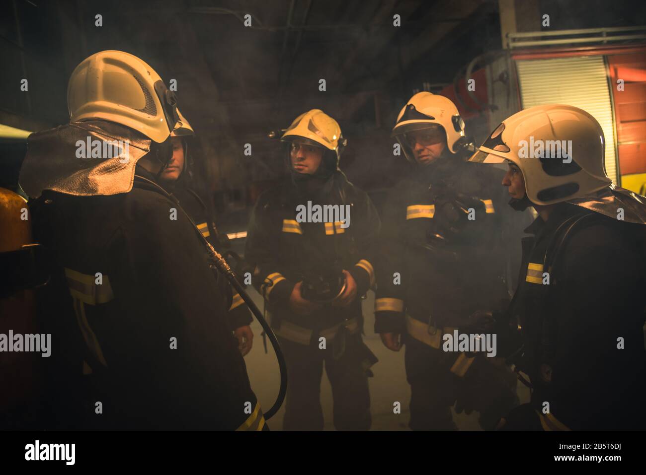 Group of firefighters with uniform inside the fire station preparing ...