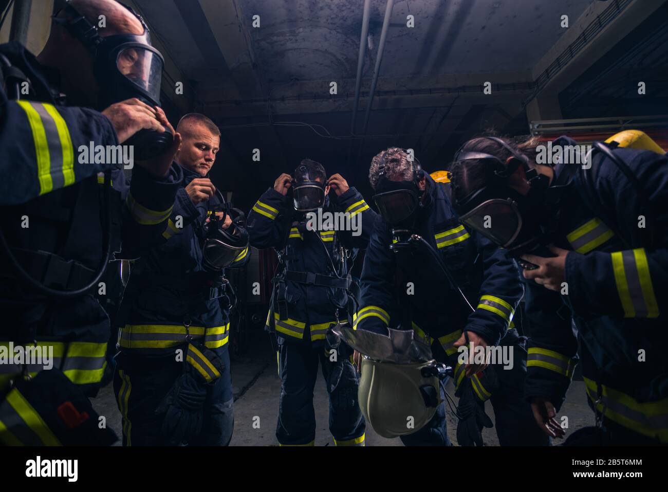 Group of firefighters standing inside the fire brigade wearing helmet ...
