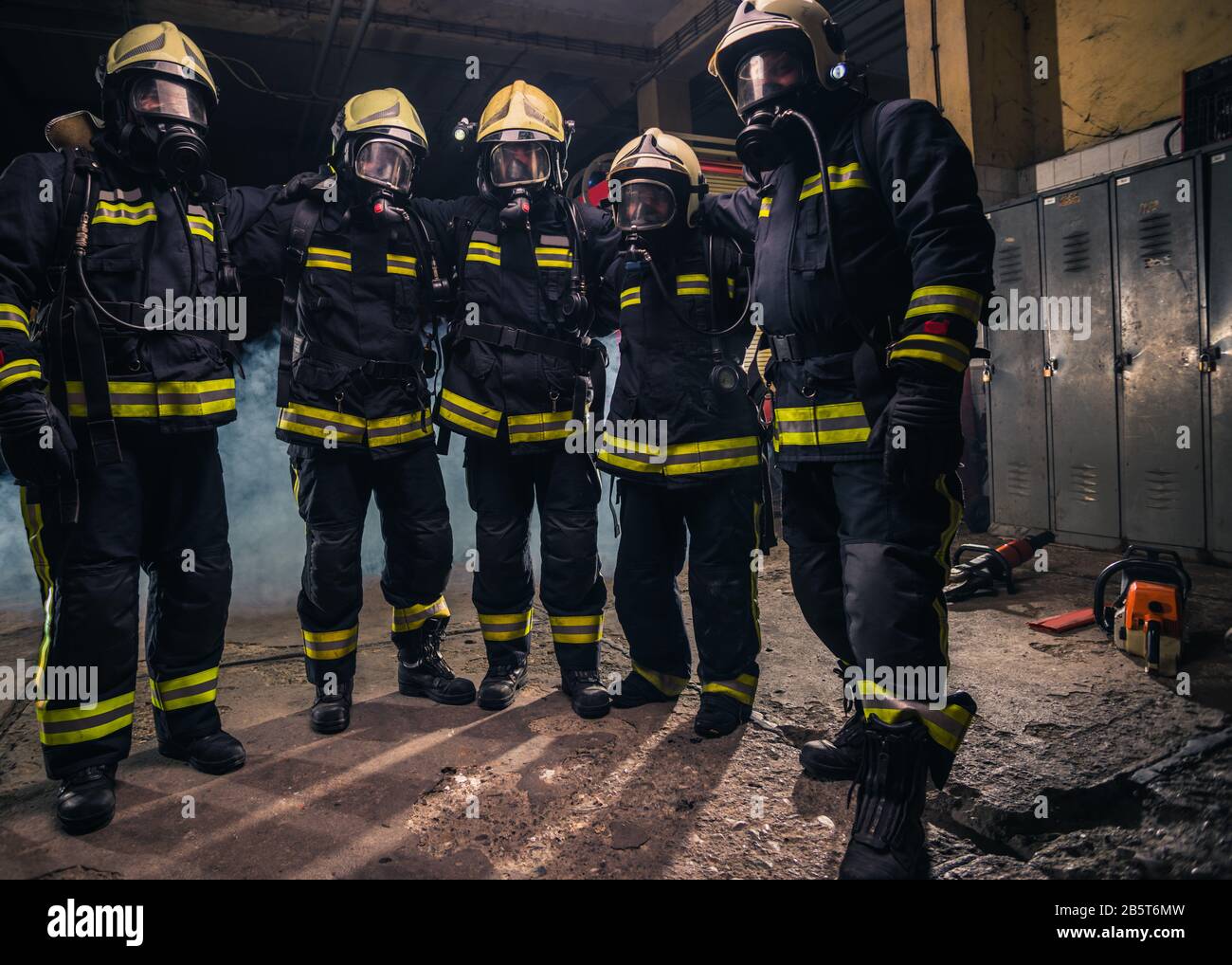 Team of firemen in uniform with gas masks inside the fire department ...