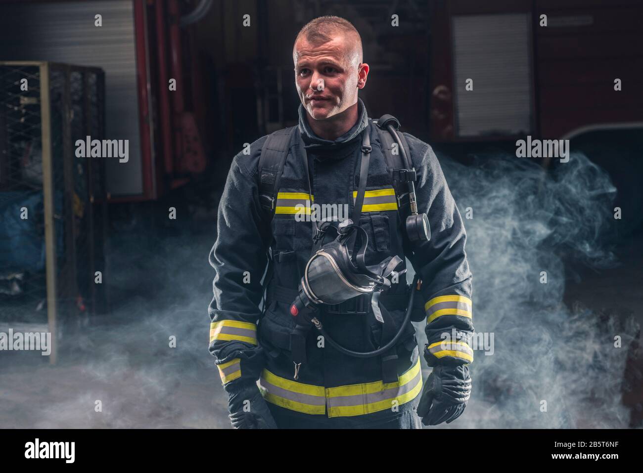 Portrait of a fireman wearing firefighter turnouts and helmet. Dark ...