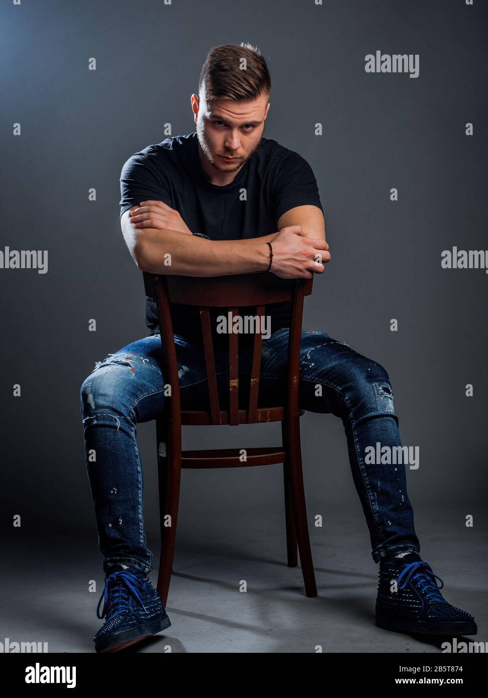 Studio fashion portrait of a young man wearing denim blue jeans and ...