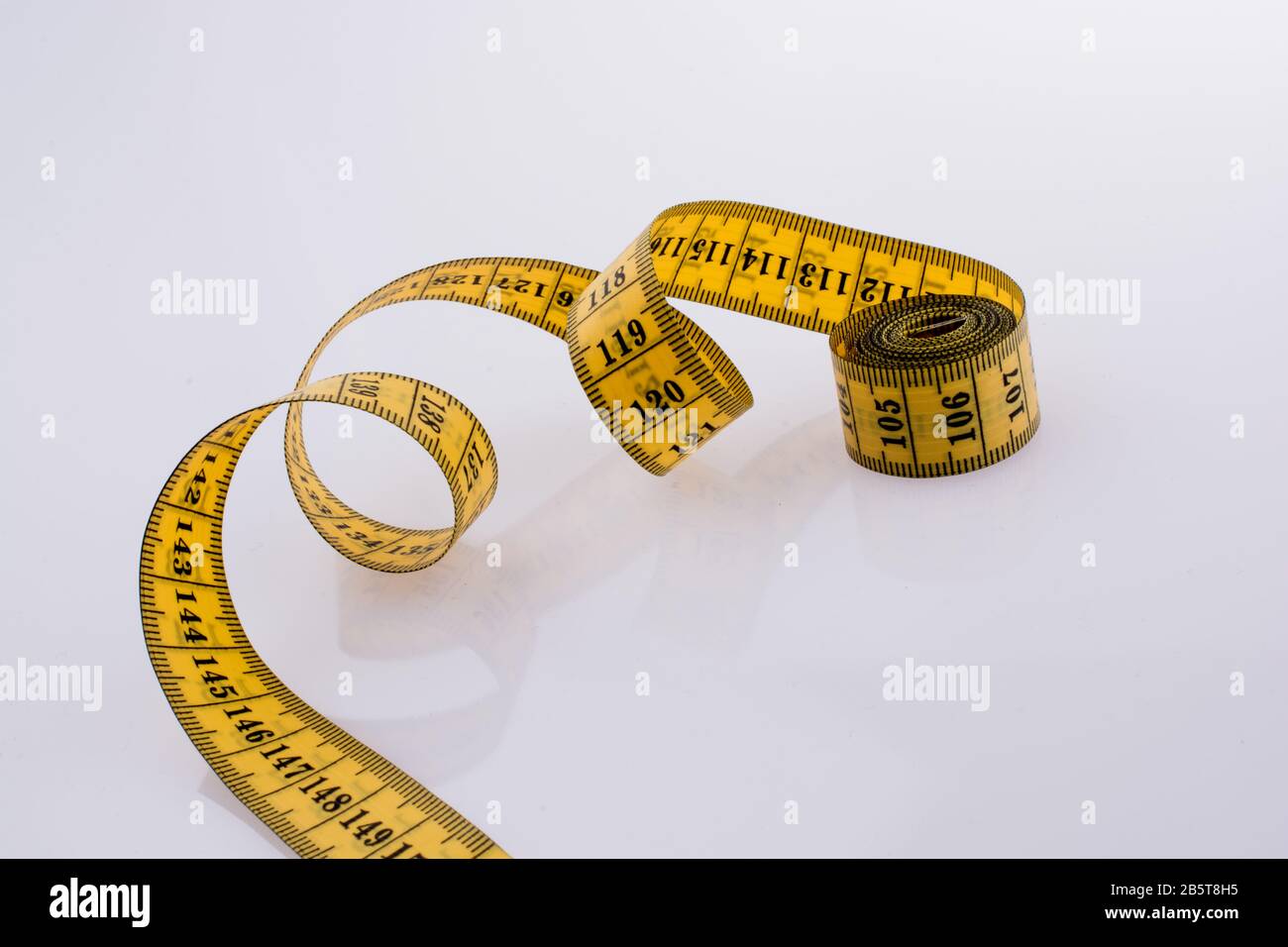 Yellow color measuring tape on a white background Stock Photo - Alamy