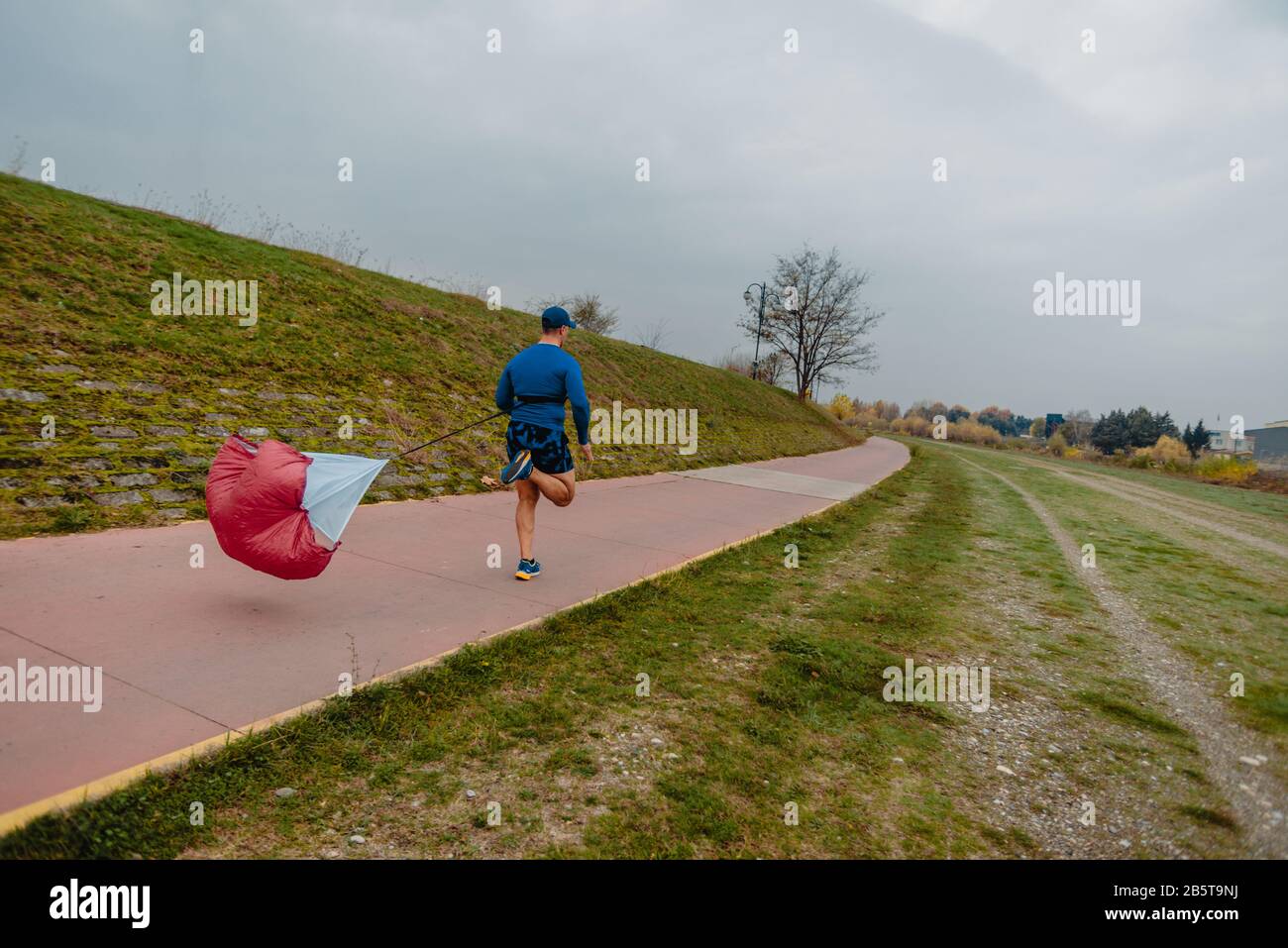 Muscular older runner dressed in fitness wear sprinting outdoors with a ...