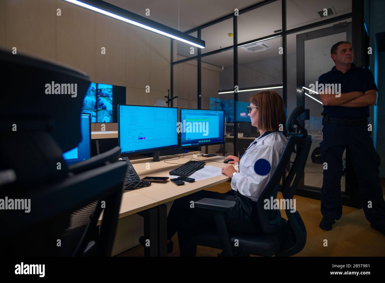 Female security guards working on computers while sitting in the main ...