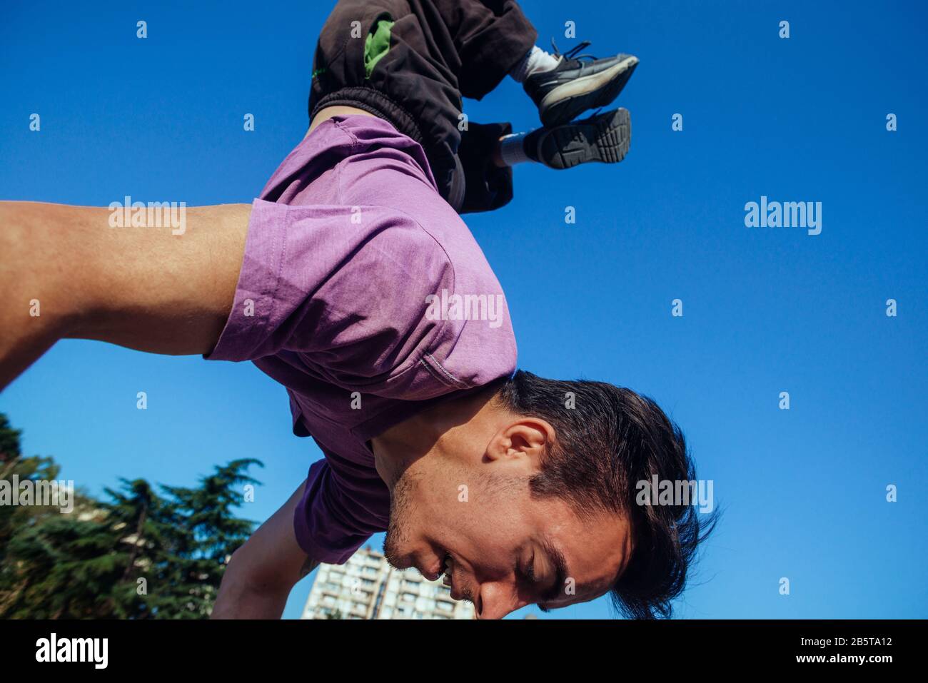 Physically strong man supporting his body on his hands at a skatepark ...