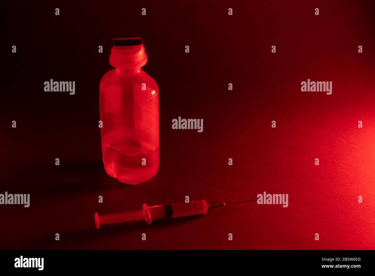 Syringe for injection and medicine in a transparent container on a gray ...