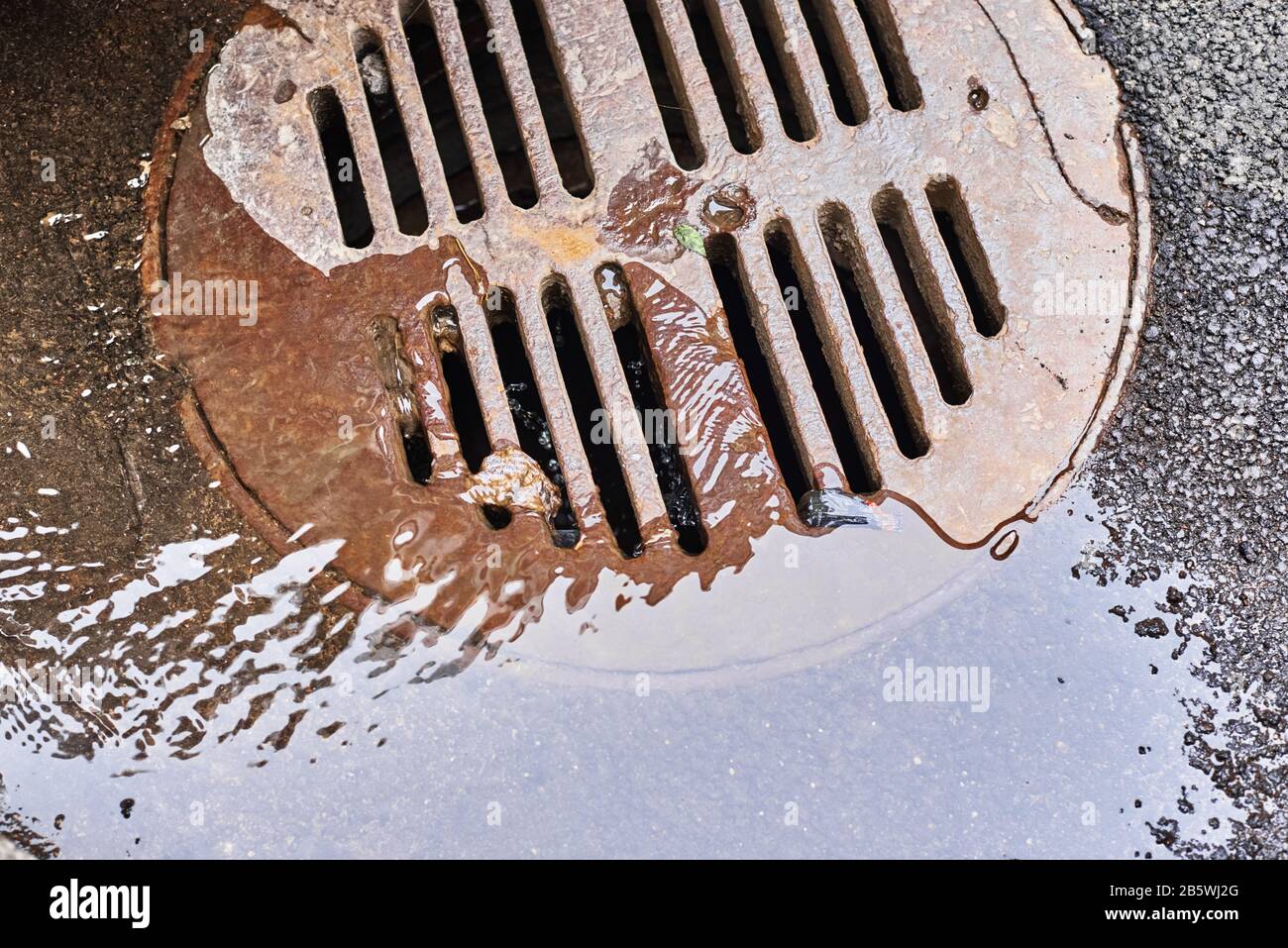 Water draining into a sewer manhole after rain on city street Stock ...