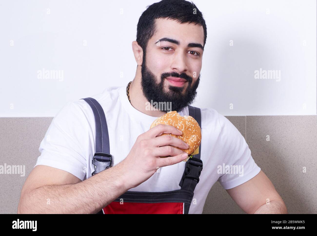 Worker wearing uniform eating burger during lunch break Stock Photo - Alamy