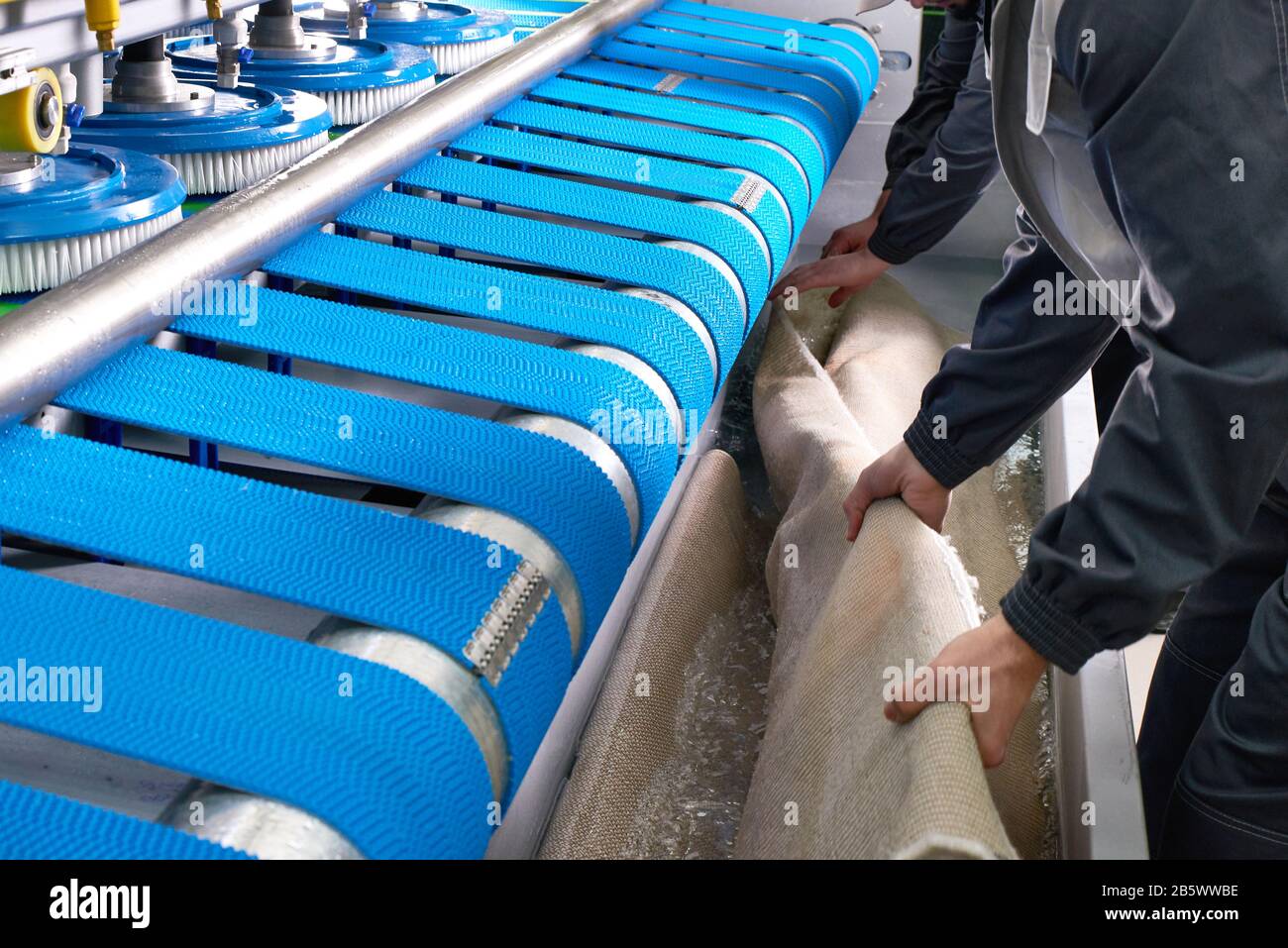 Laundry worker in the process of working on automatic machine for ...