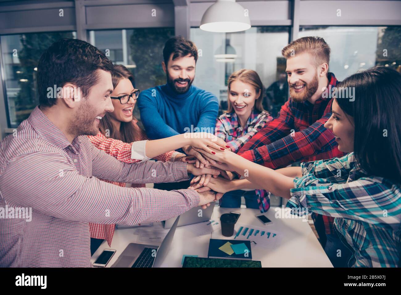 Happy businesspeople working together and putting hands on top of hands ...