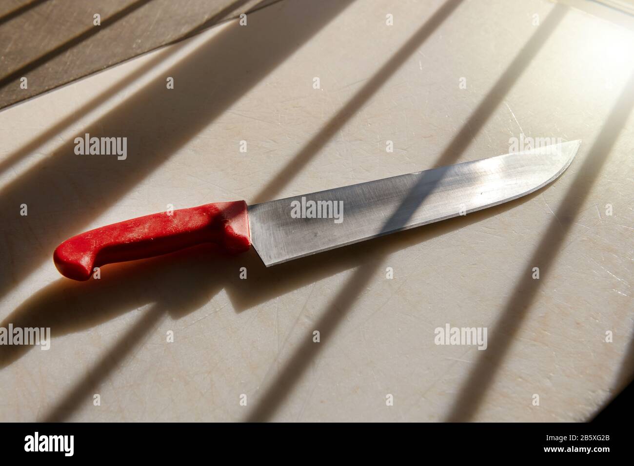 Butchers knife with red handle, viewed in close-up, sitting on white ...
