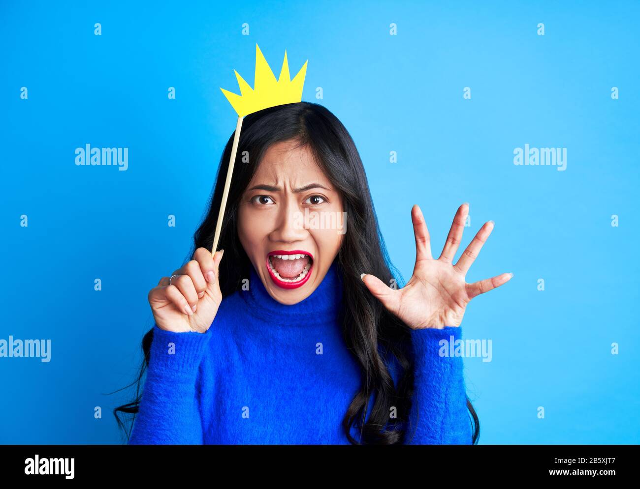 Angry screaming woman with paper crown on stick isolated on blue ...