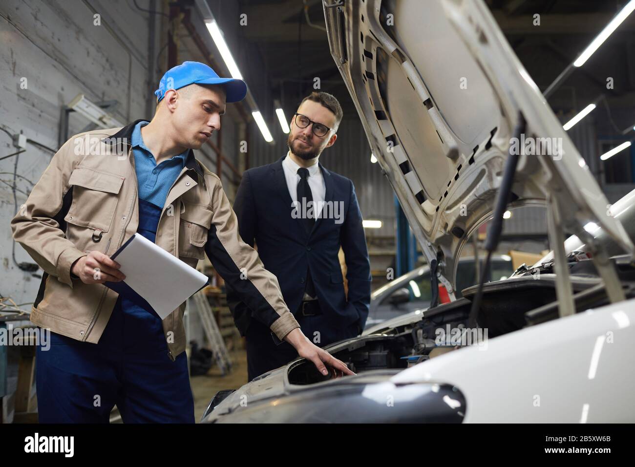 Horizontal low angle shot of professional auto mechanic demonstrating ...
