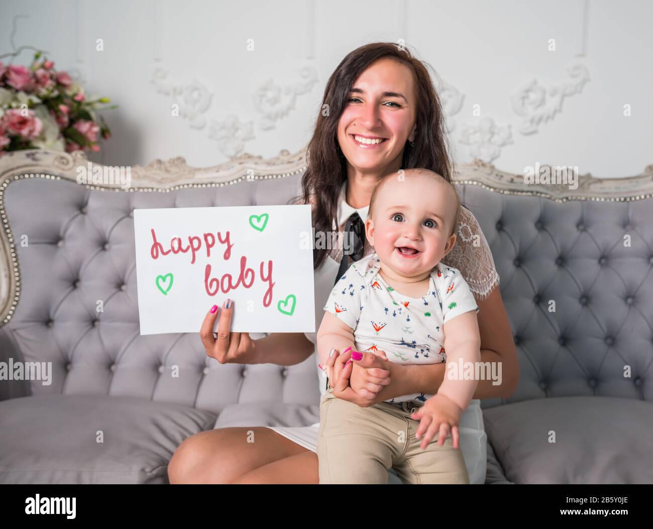 Young woman and son holding paper in the arms. Small restless child ...