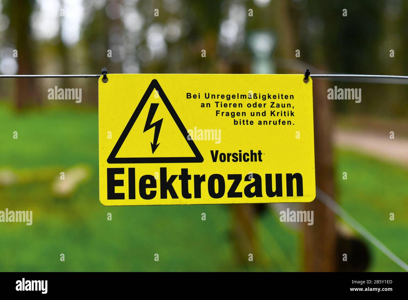 Yellow electric fence warning sign with German text saying `Attention ...