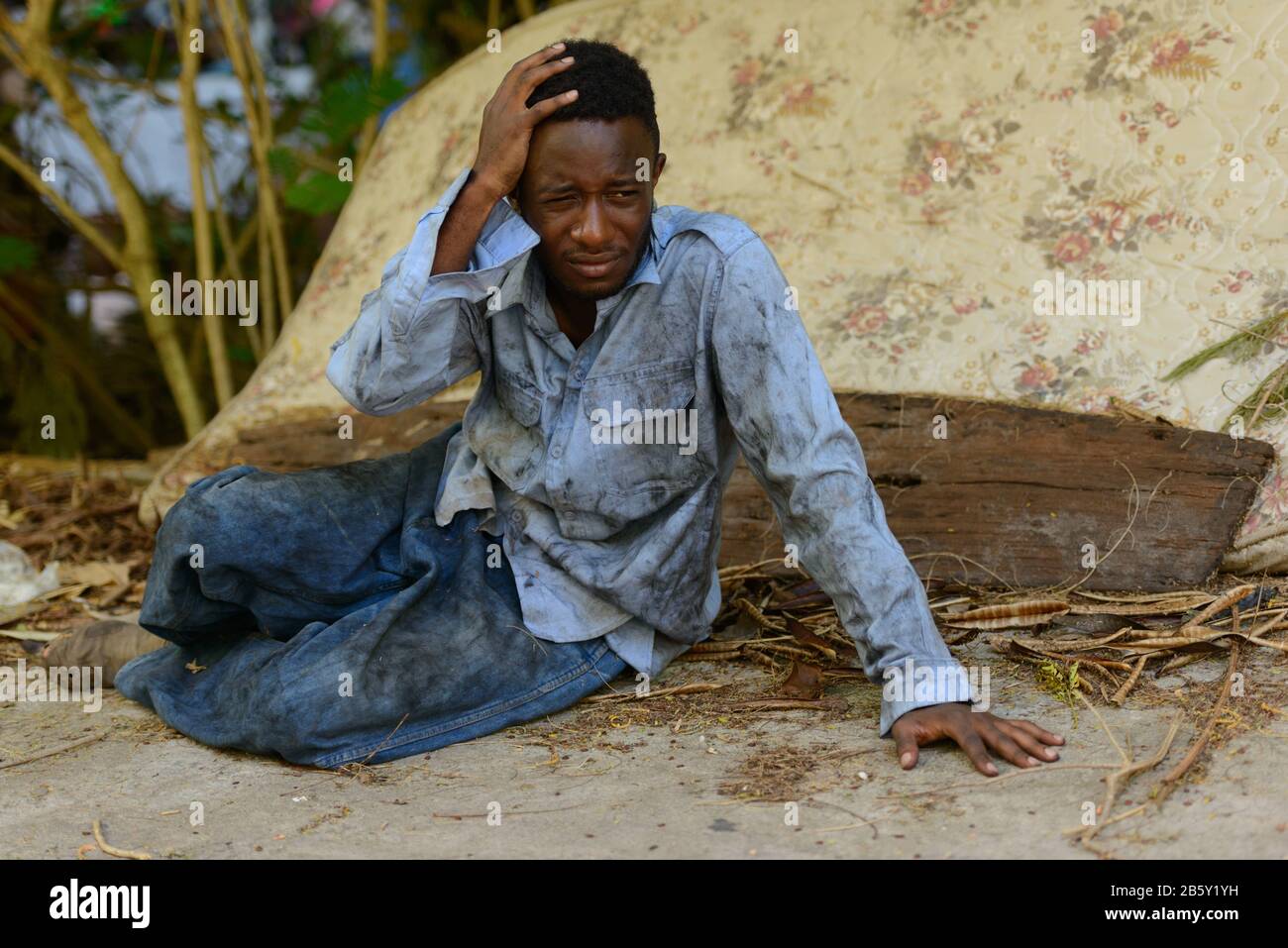 Stressed young homeless African man sitting in the streets Stock Photo ...