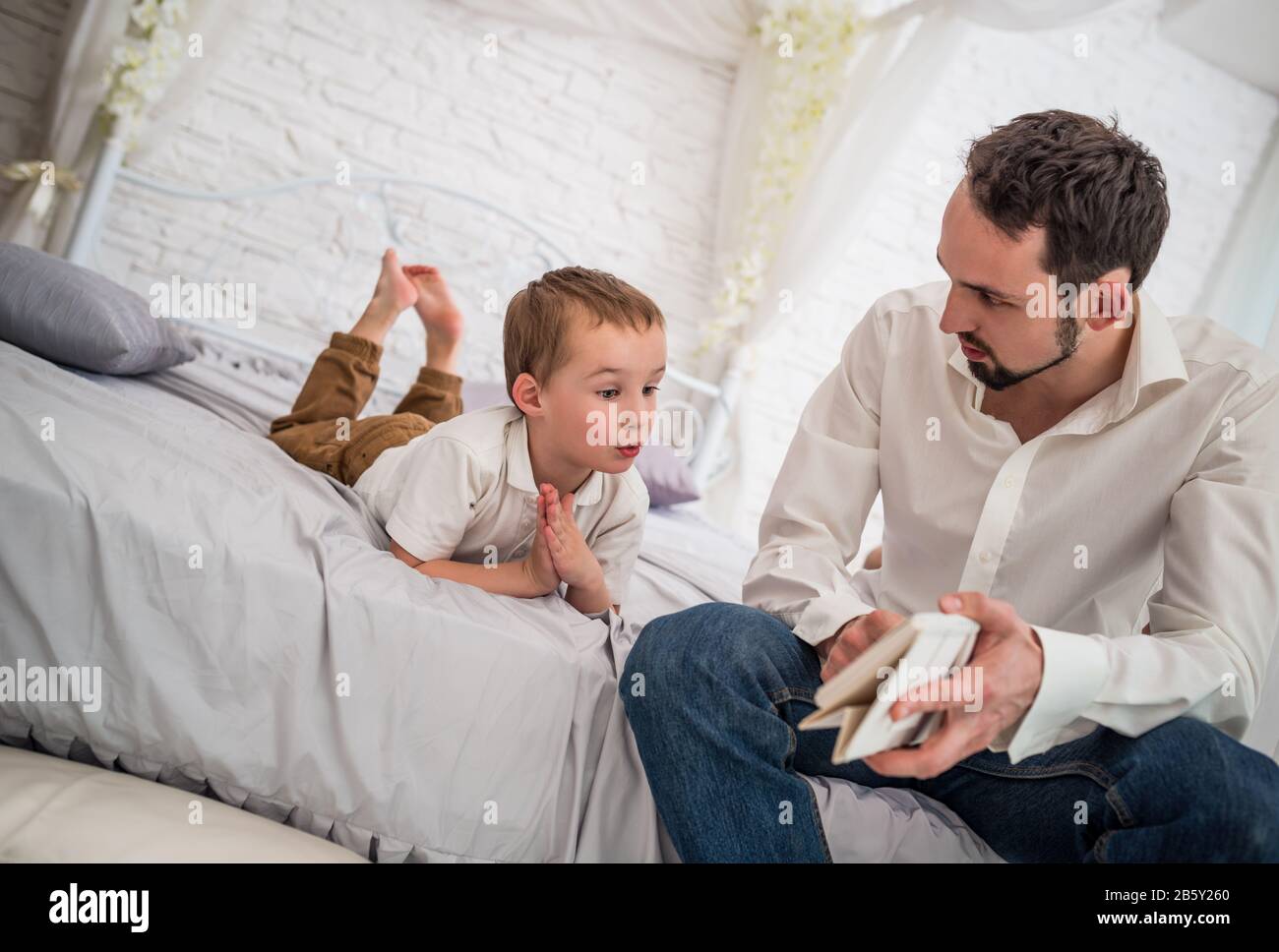 Young serious father is talking with his curious little son holding a ...