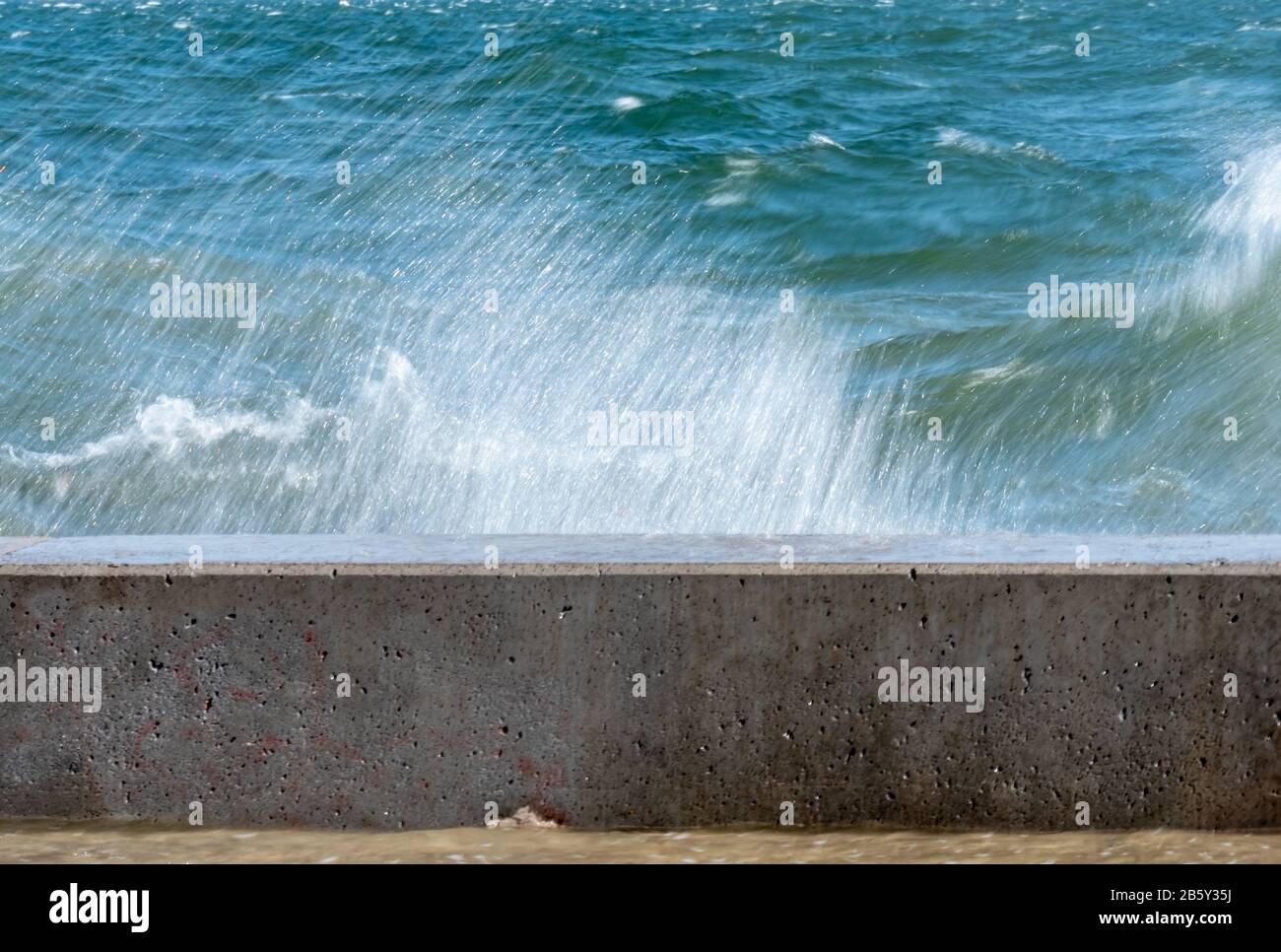 Waves hit the hard surface of concrete wall and splashing sea water ...