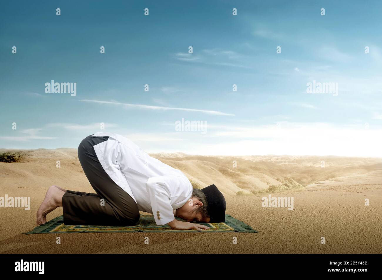 Asian Muslim man with a prayer rug in a praying position (salat) on the ...