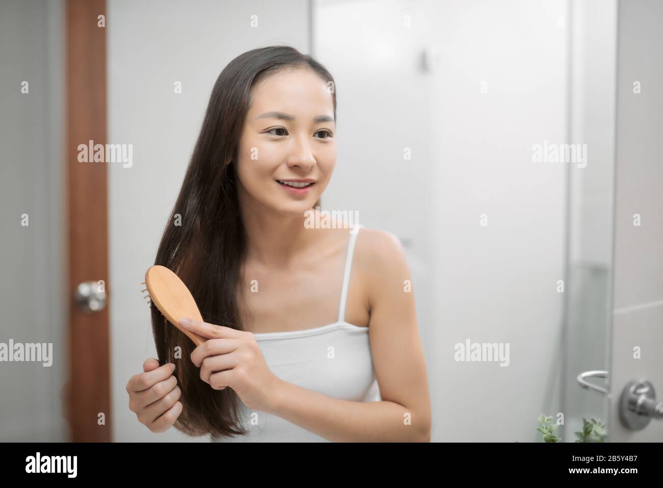 Closeup on young woman combing hair Stock Photo - Alamy