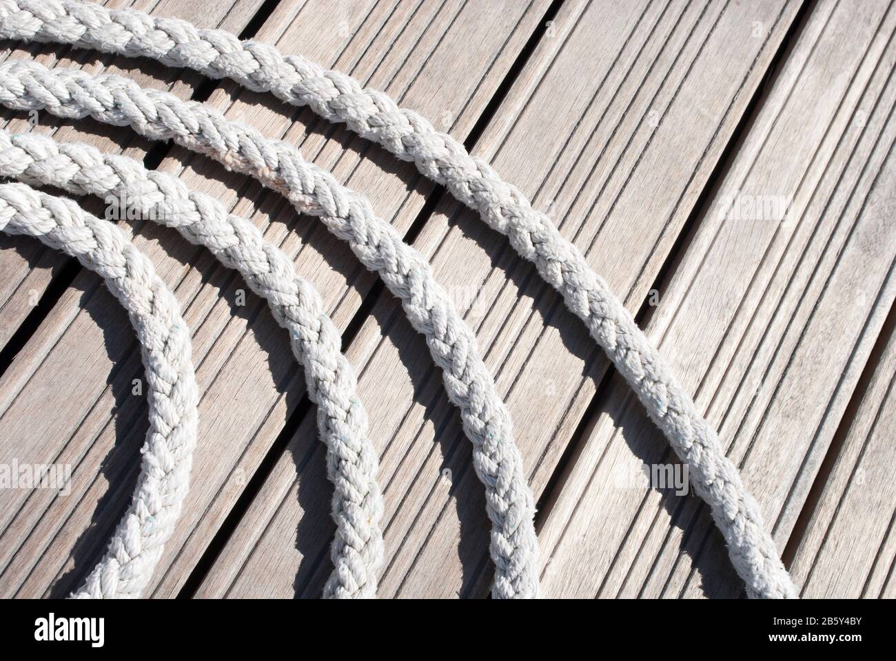 Thick white nautical rope forming a loose abstract spiral outdoors on a ...