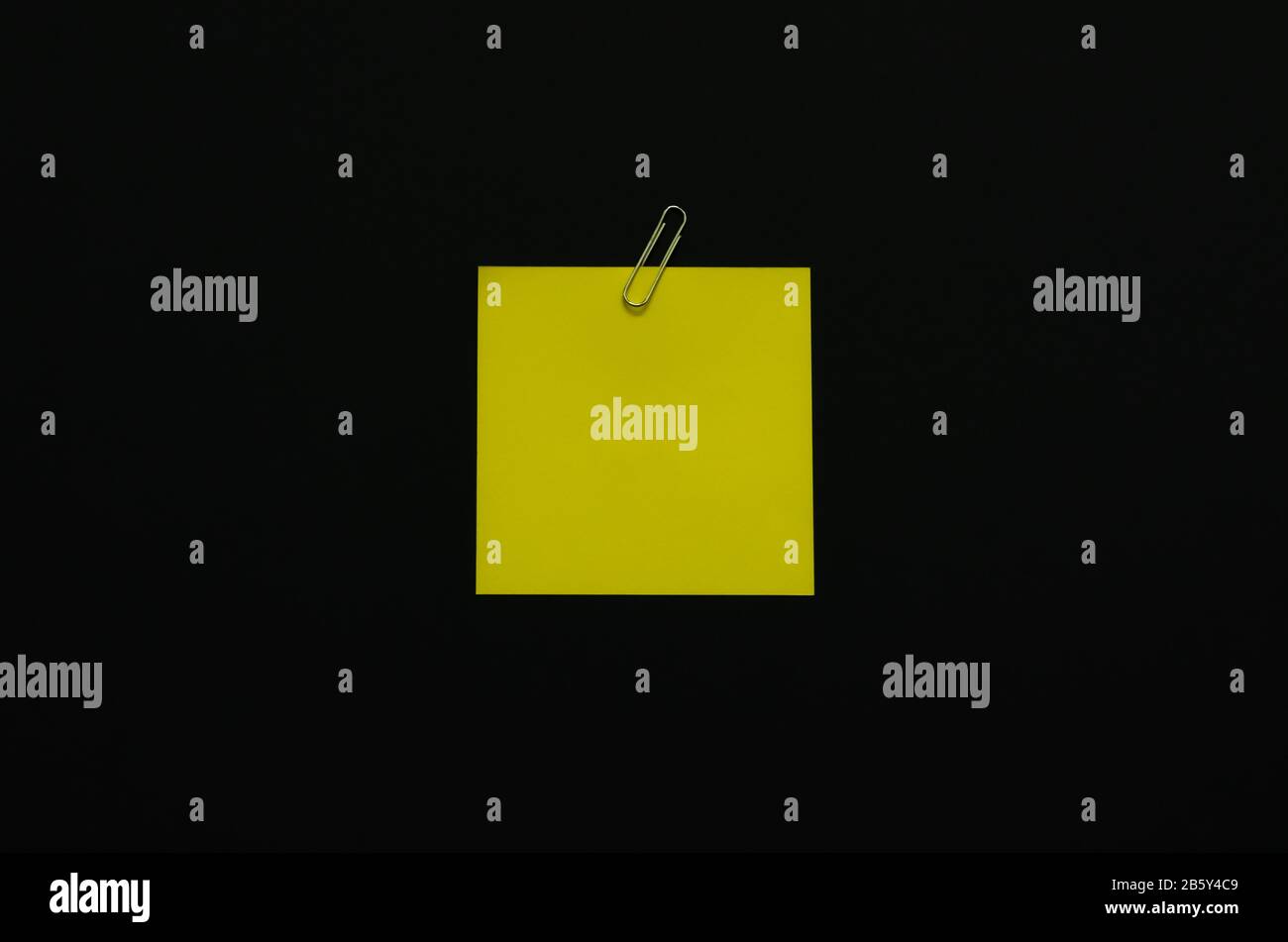 Yellow blank note paper with paper clip on dark background. Minimalist ...