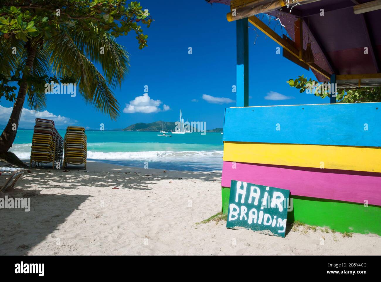 Rustic handwritten sign for hair braiding leaning in the sand against a ...