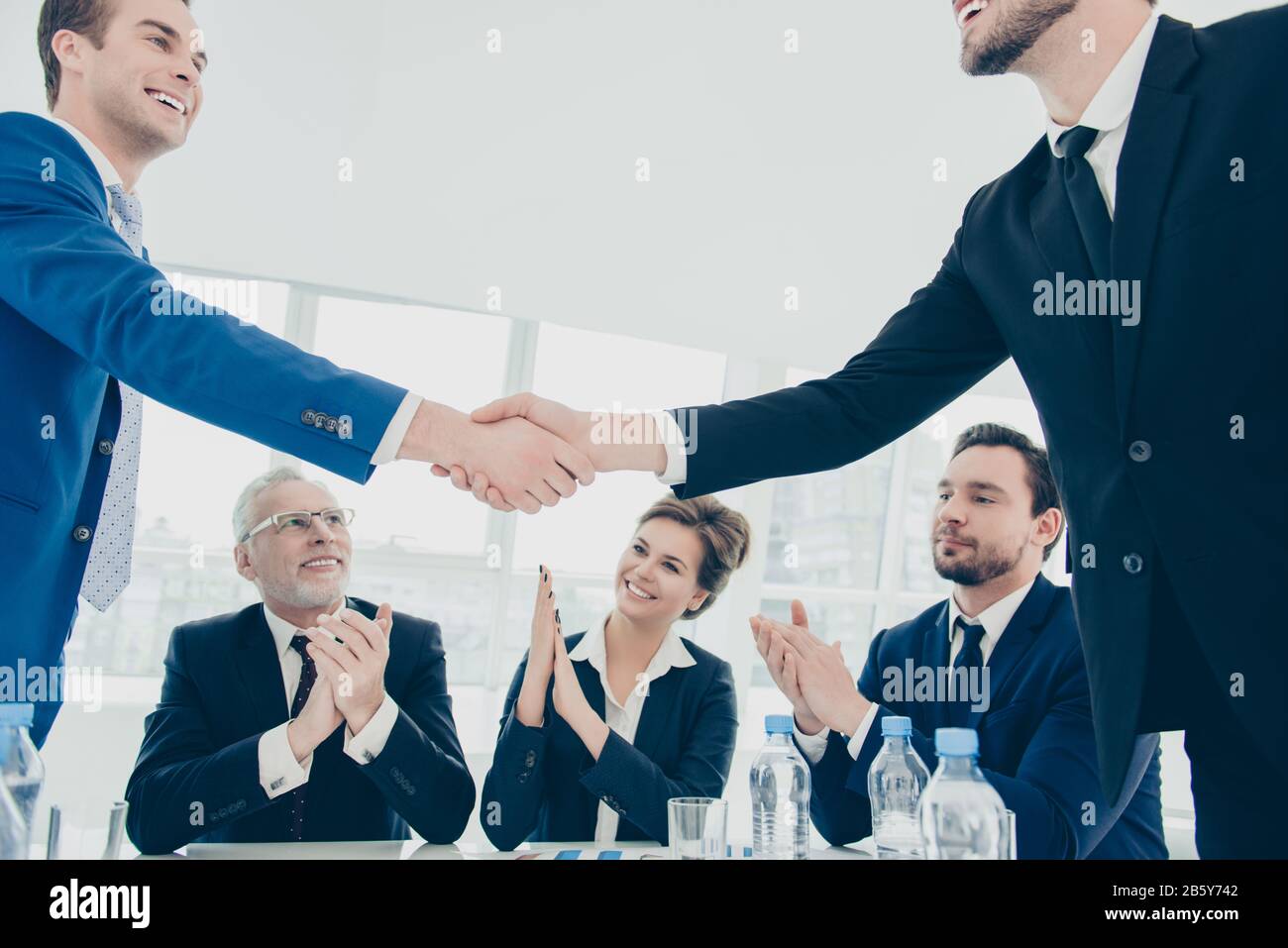 Deal! Two happy colleagues shaking hands Stock Photo - Alamy