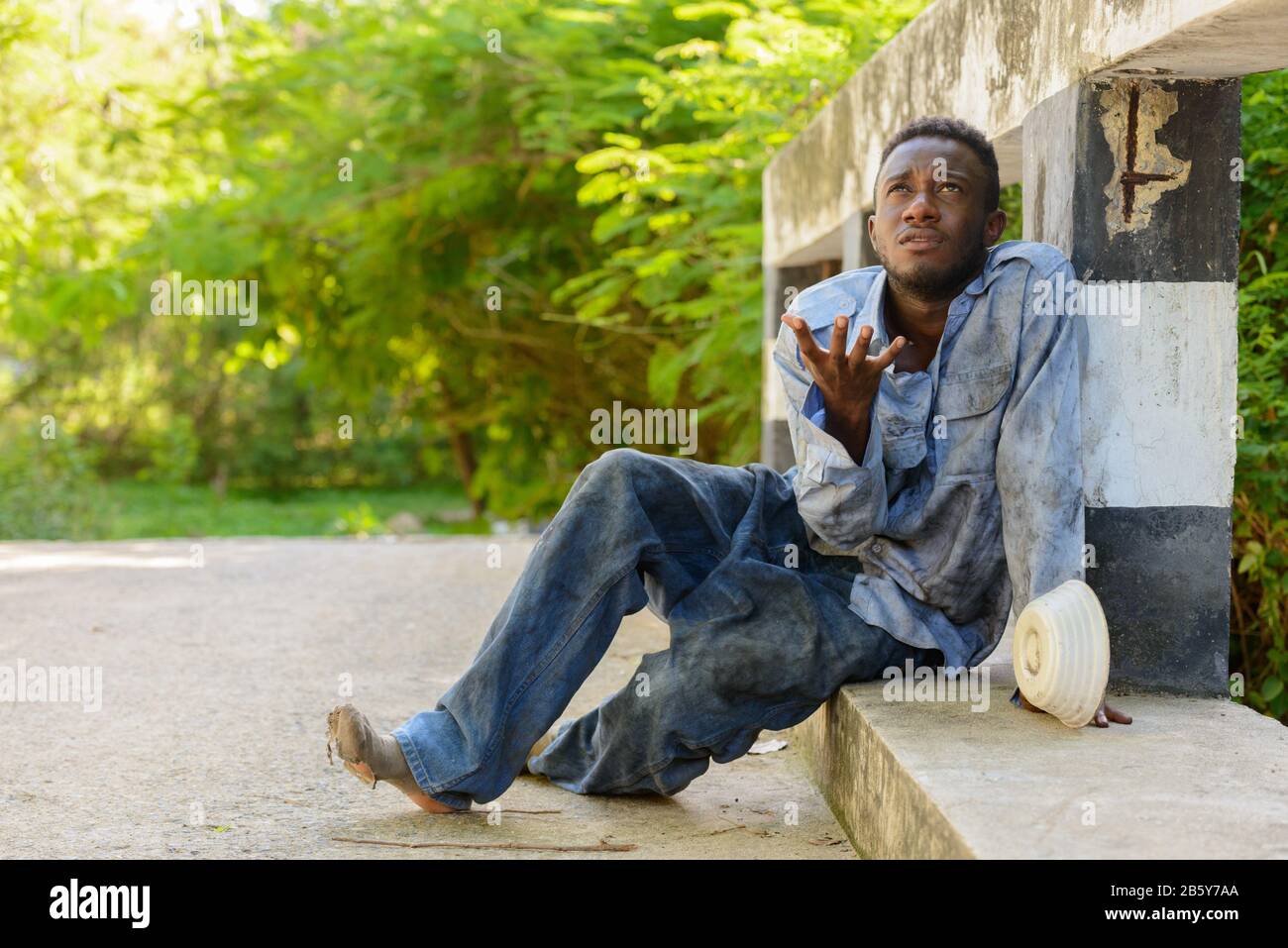 Young homeless African man begging for food on the bridge Stock Photo ...