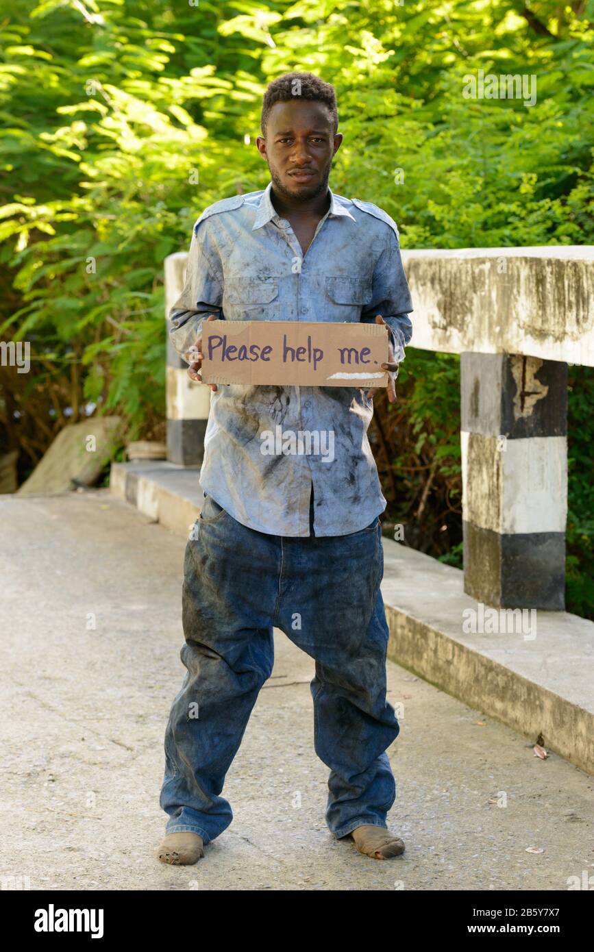 Young homeless African man with cardboard sign asking for help Stock ...