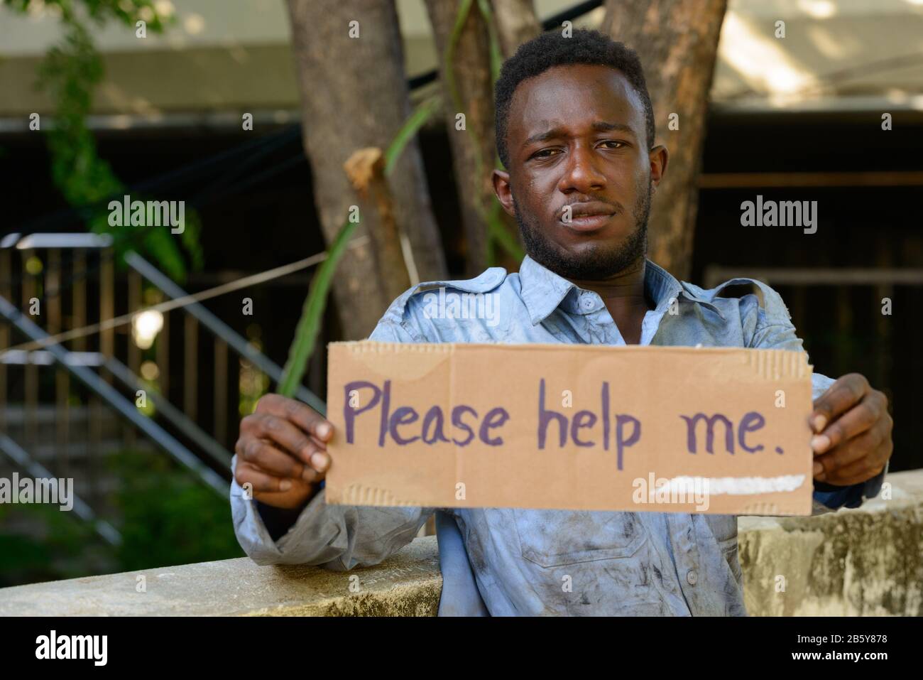 Young homeless African man with cardboard sign asking for help Stock ...