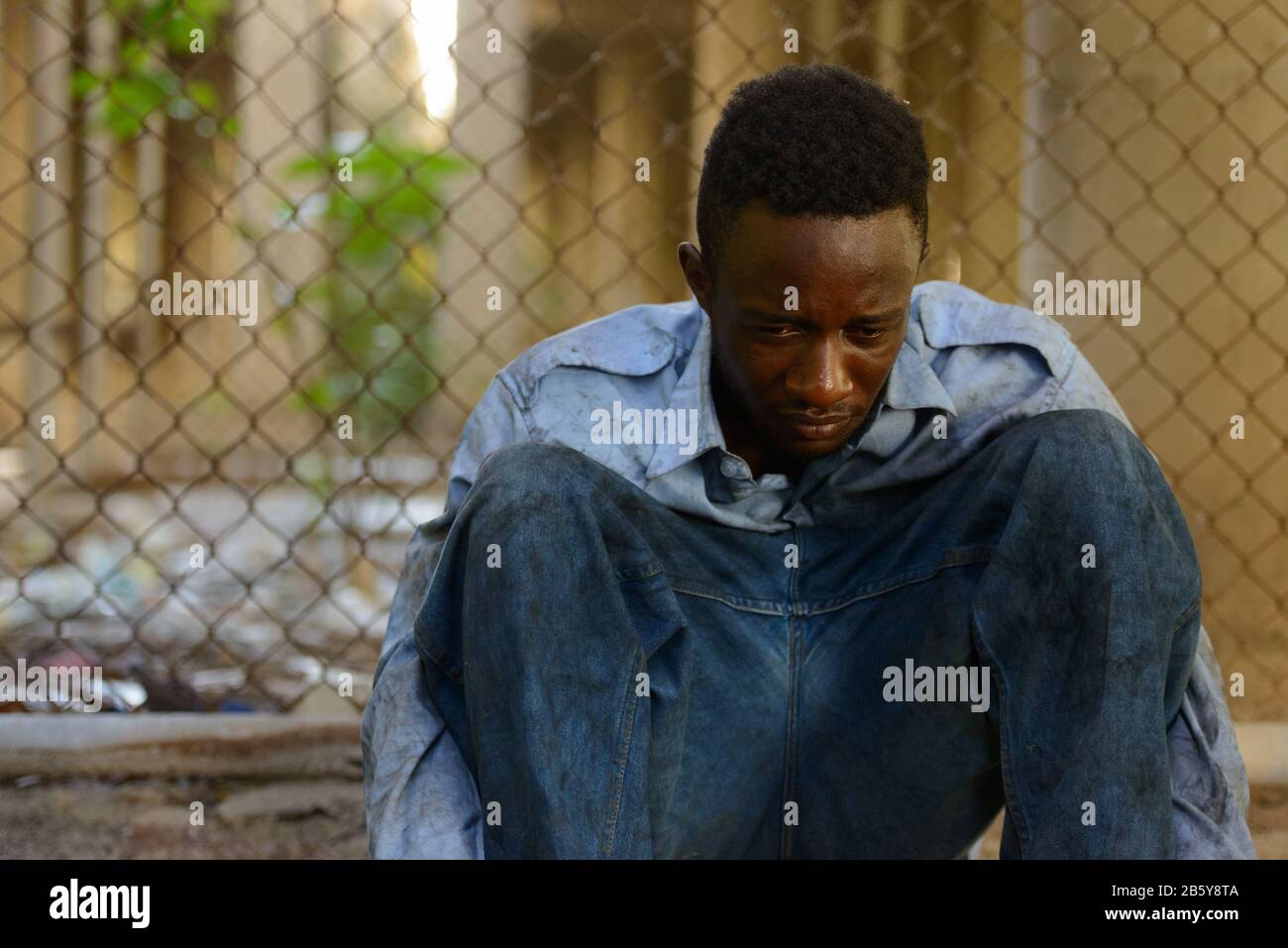 Young homeless African man sitting in the streets Stock Photo - Alamy